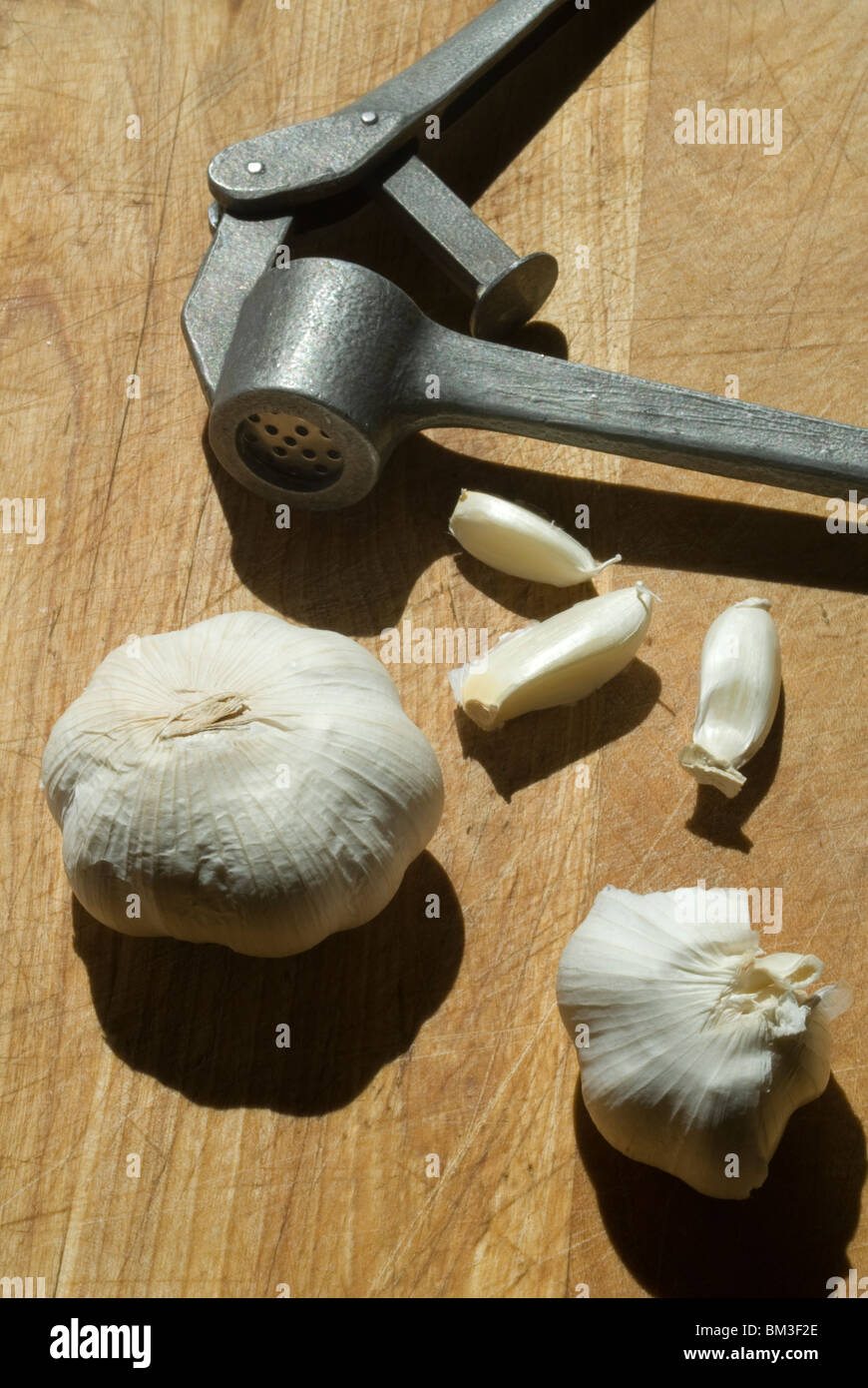 still life of garlic on a chopping board with an old garlic press Stock ...