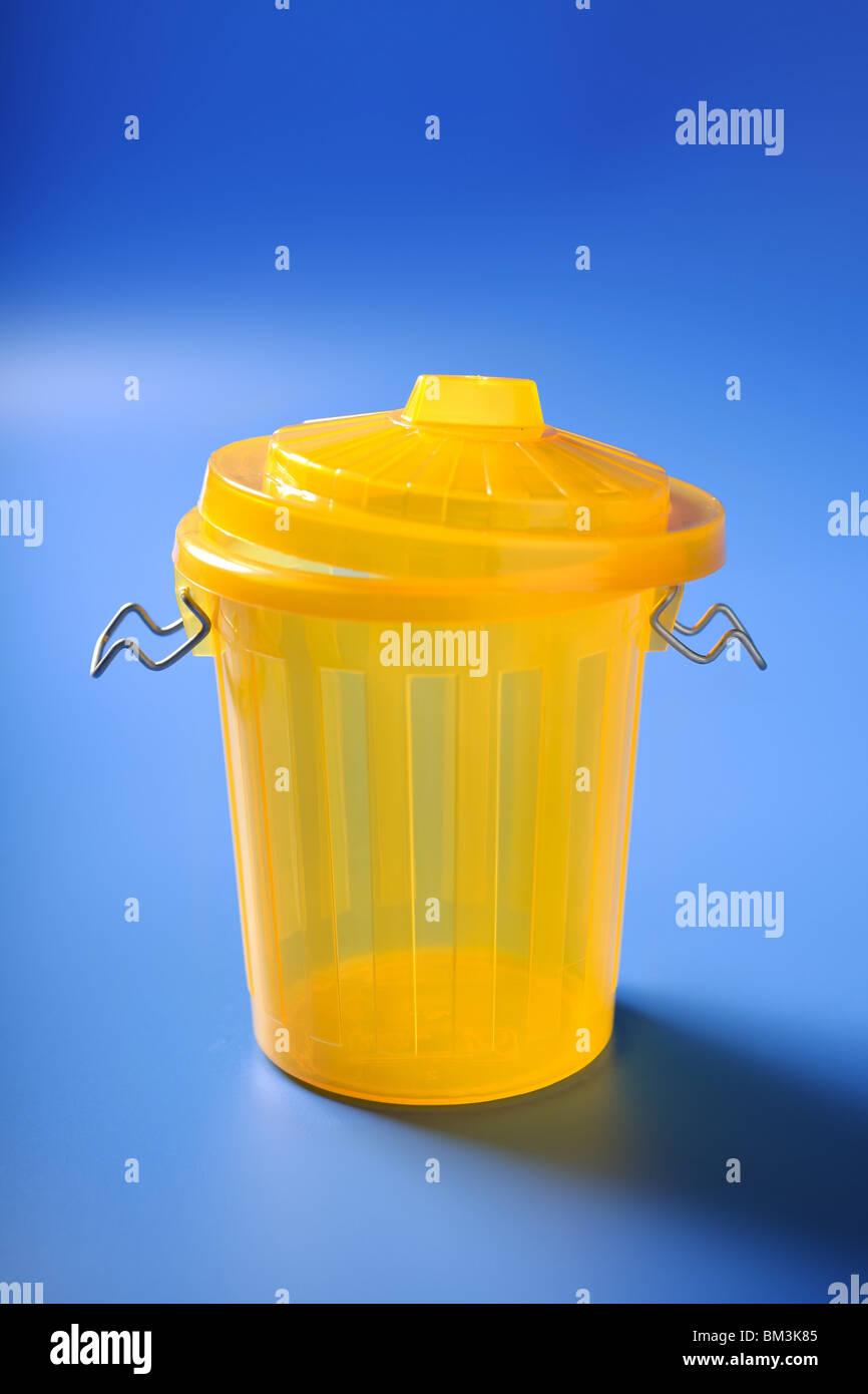 Yellow trash dustbin over blue background with shadows Stock Photo - Alamy