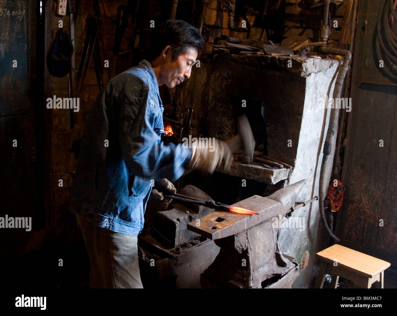 A blacksmith knocks into shape the head of a pickaxe in his workshop in ...