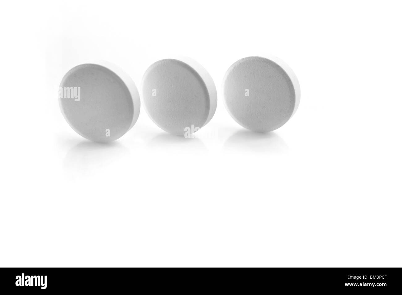 Three isolated white round pills in a row Stock Photo - Alamy