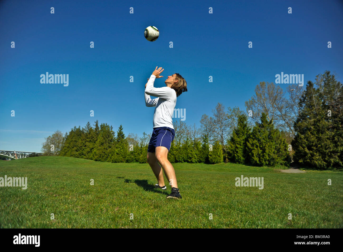 A young Caucasian guy practicing soccer skills out in a park Stock ...