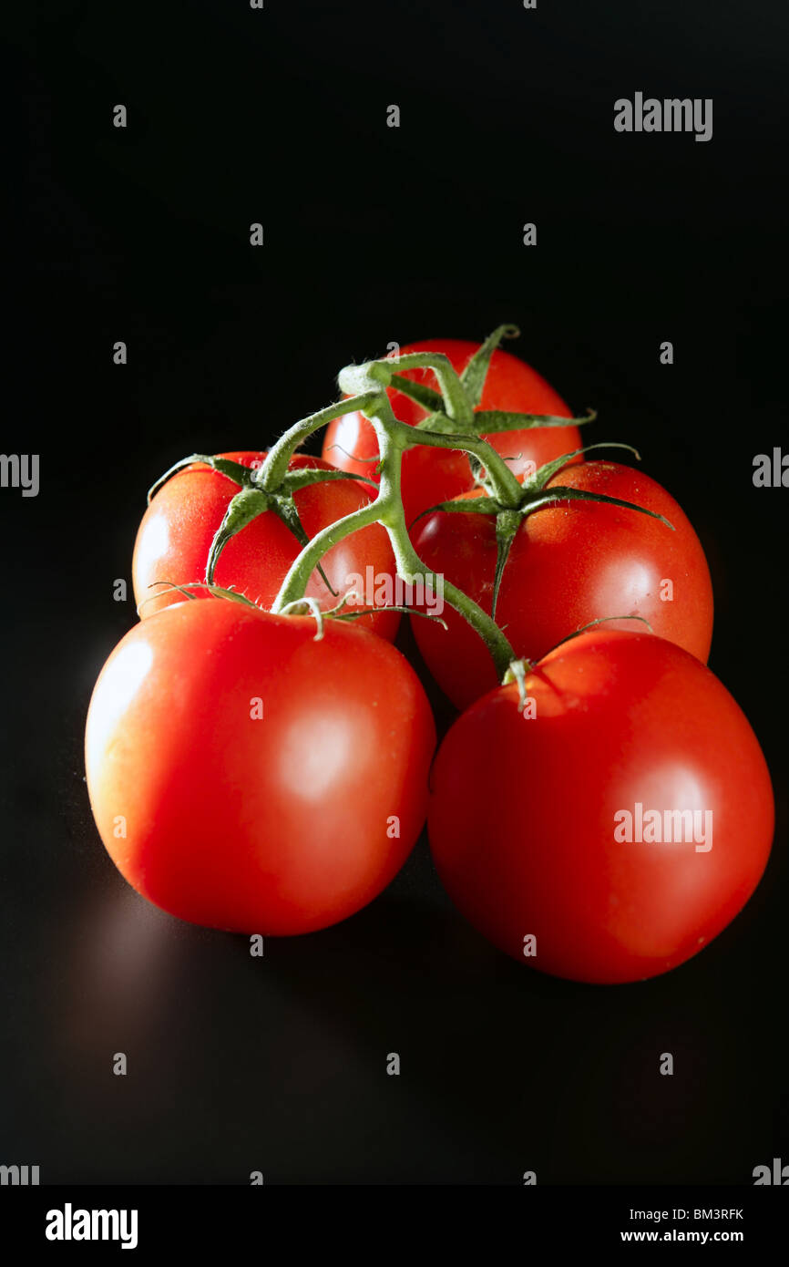 Cluster red tomato over dark black background Stock Photo - Alamy