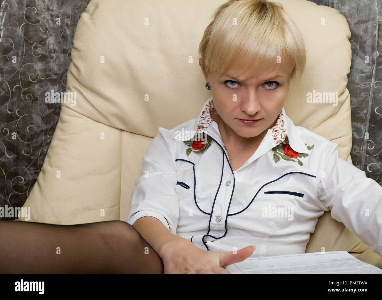 beautiful girl with a defiant look sits in an office laying a leg on a ...