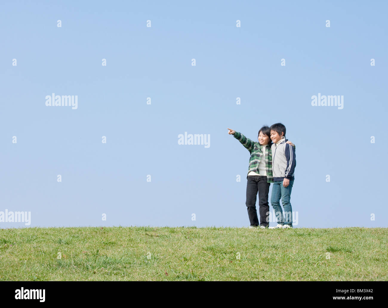 Two Boys Standing Under Blue Sky, Pointing at the Sky Stock Photo - Alamy