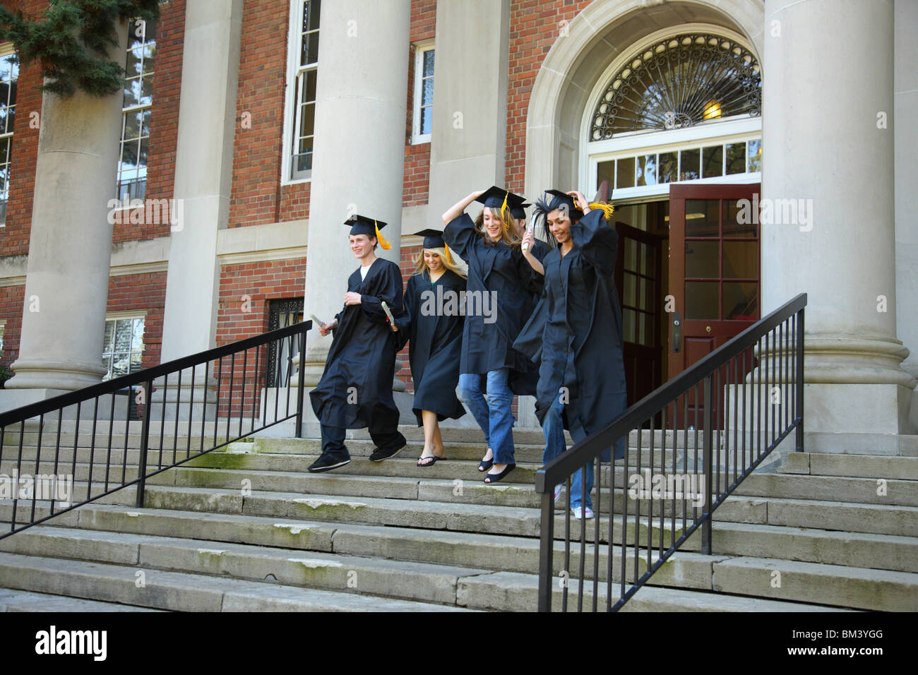 Group of graduates running down steps of school Stock Photo - Alamy