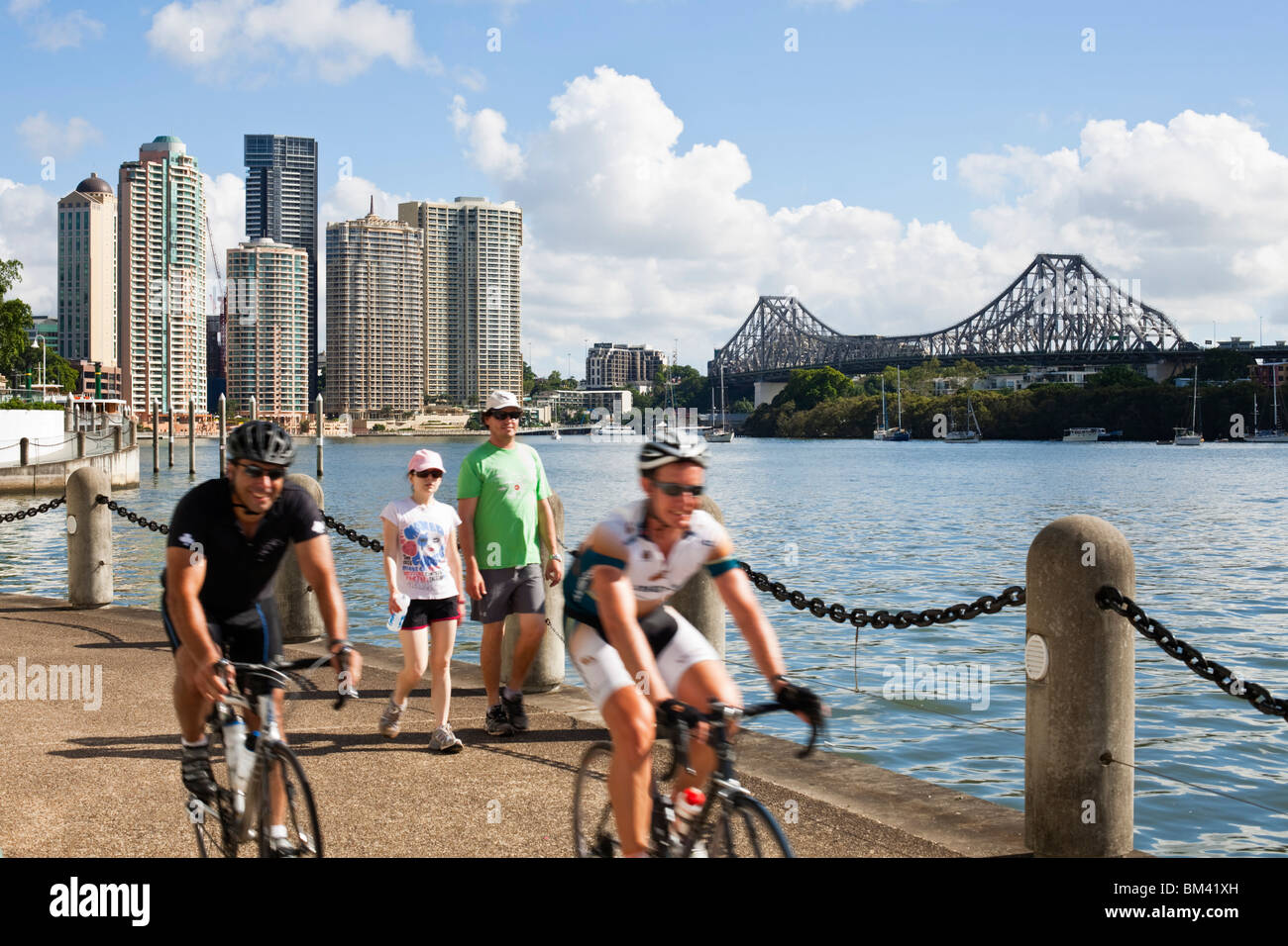 Cyclists on the r iverside with Story Bridge in the background ...