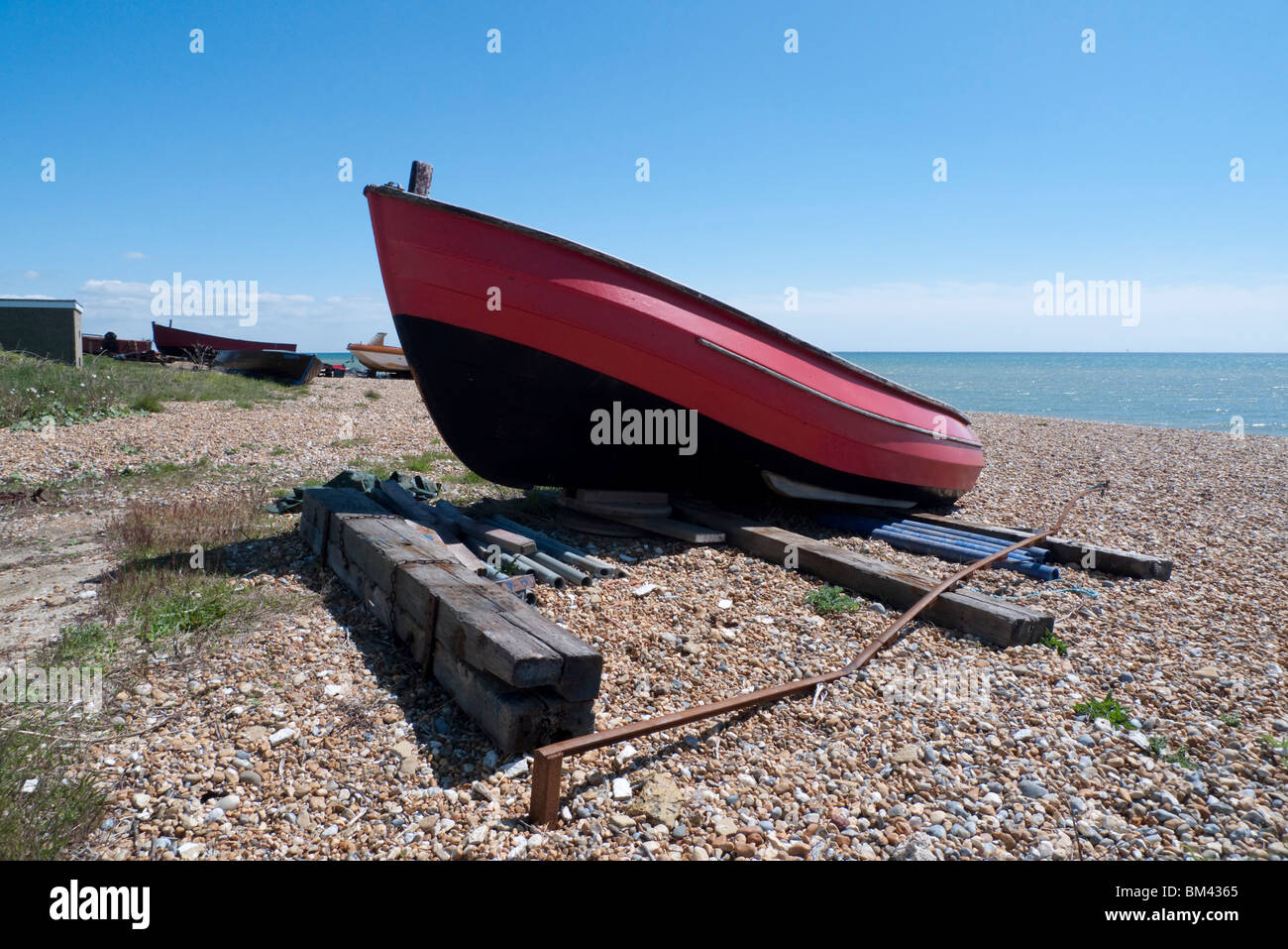 A red and black rowing boat moored stored on a beach Stock Photo - Alamy