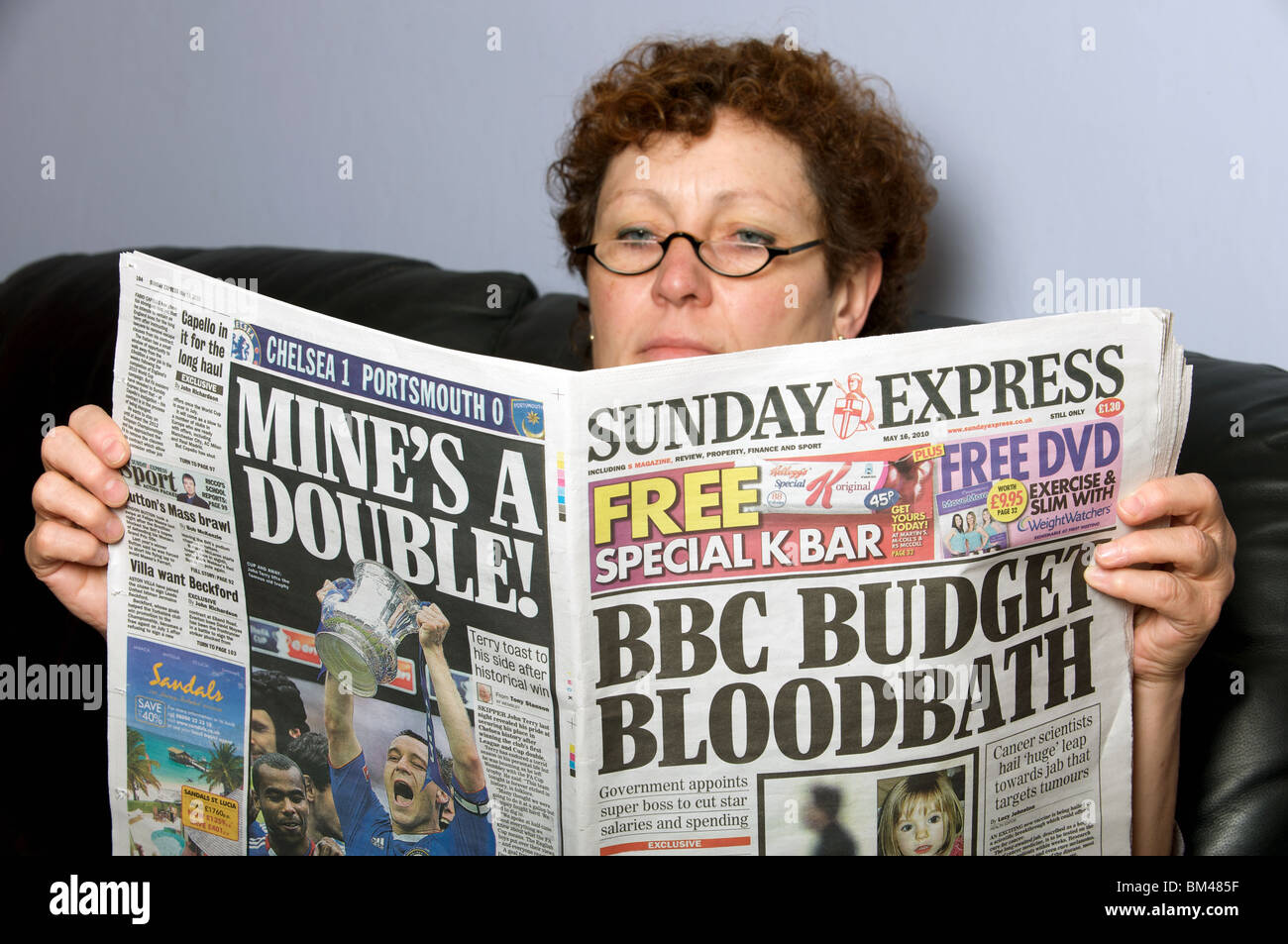 Woman reading a copy of the Sunday Express newspaper Stock Photo - Alamy