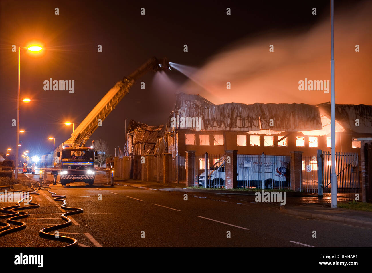 Large factory warehouse on fire at night with lots of flames and smoke ...