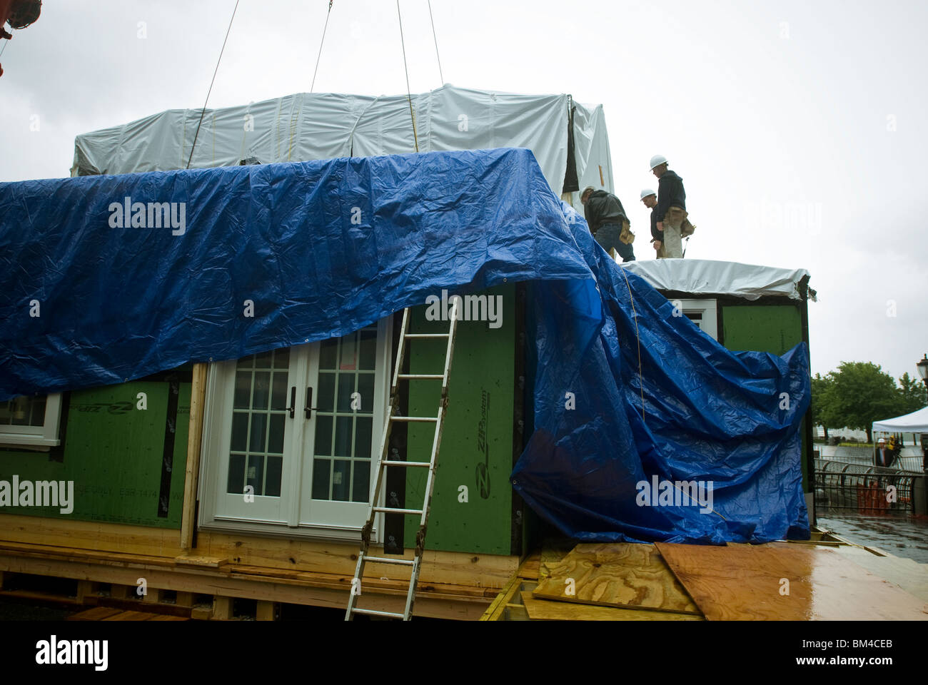 Workers construct a temporary prefabricated cottage home at the World ...