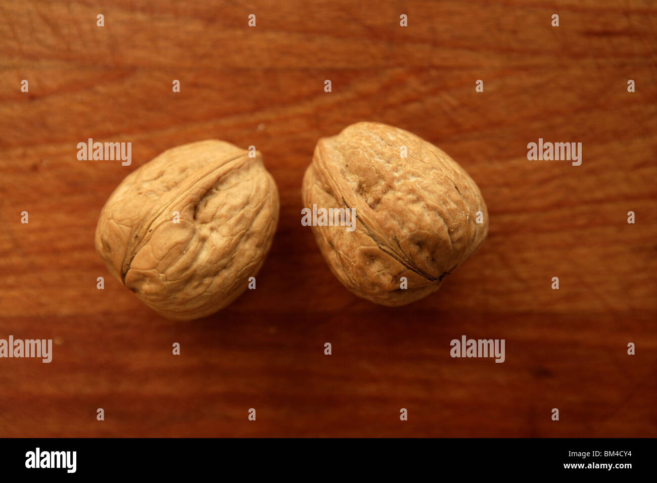 Two walnuts on a golden wood aged table Stock Photo - Alamy