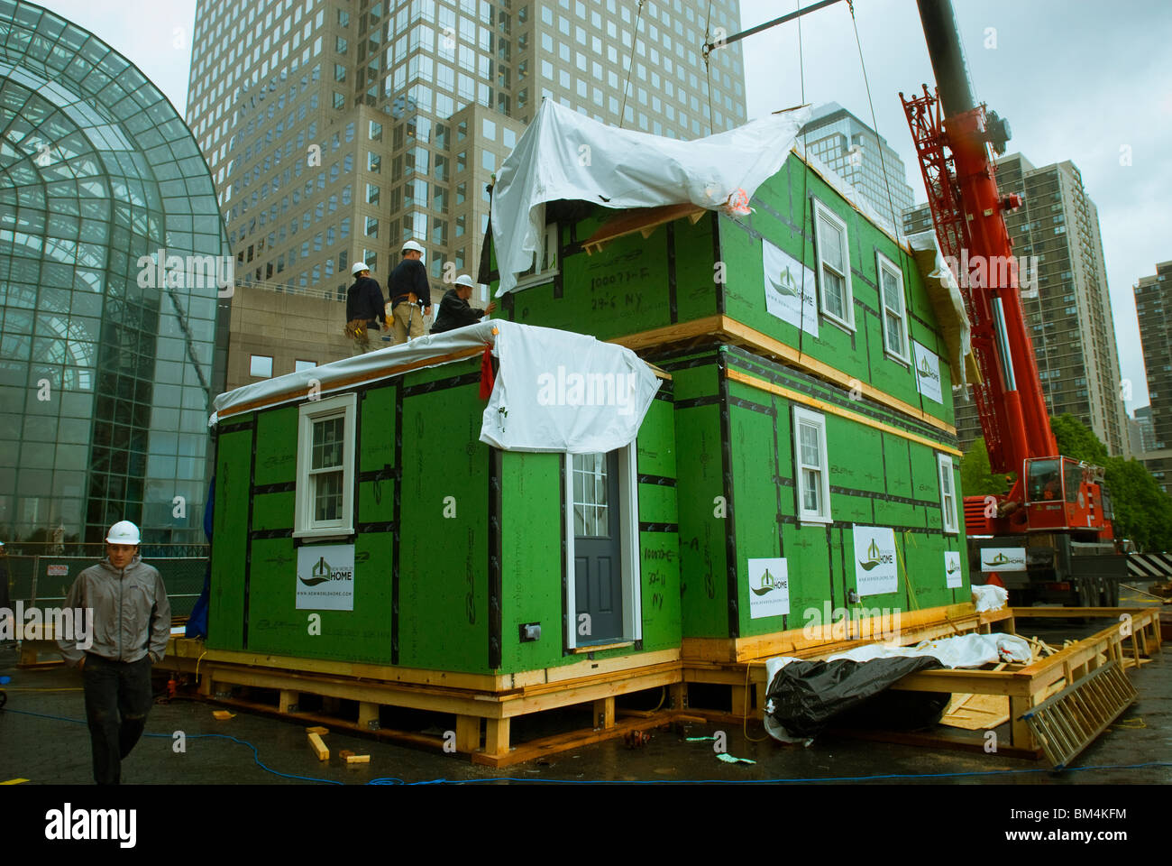 Workers construct a temporary prefabricated cottage home at the World ...