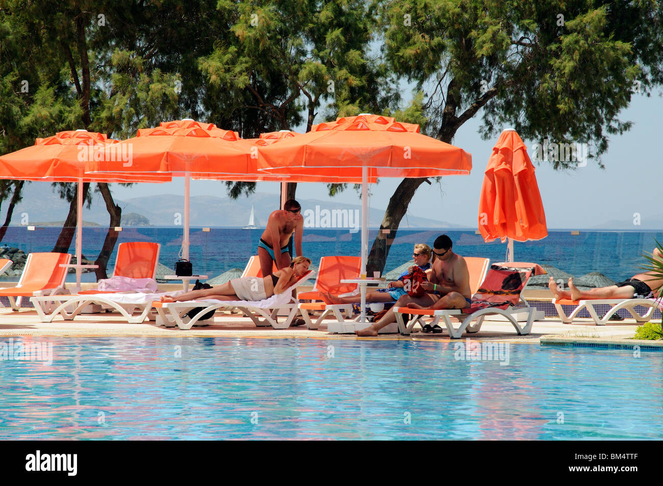 Two couples relax around a hotel swimming pool in the seaside resort of ...
