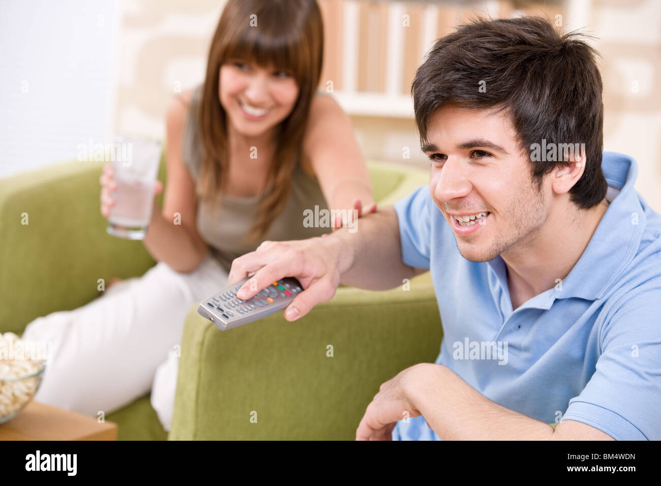 Student - happy teenagers watching television holding remote control in ...