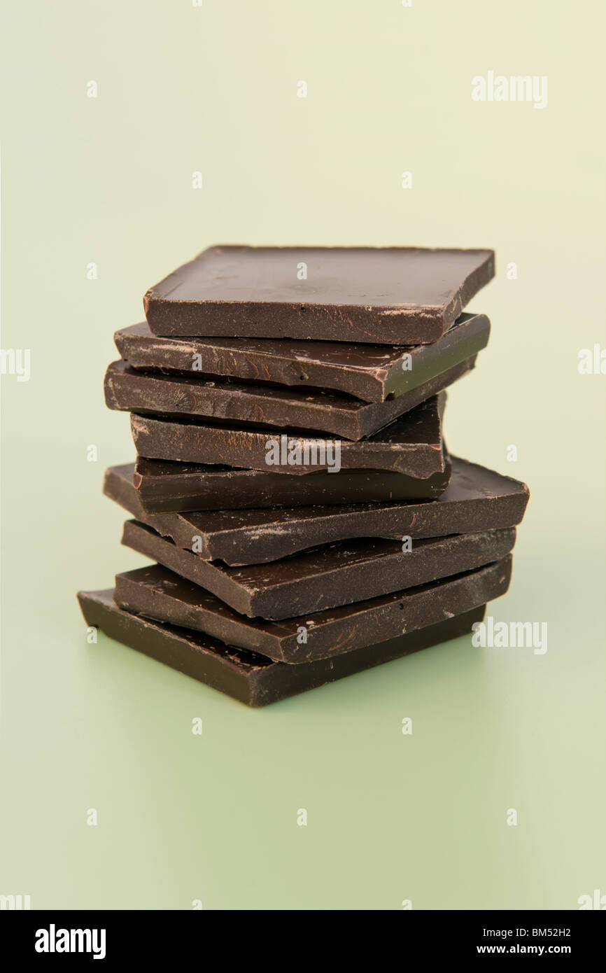 Studio shot of a stack of plain chocolate pieces against a green ...