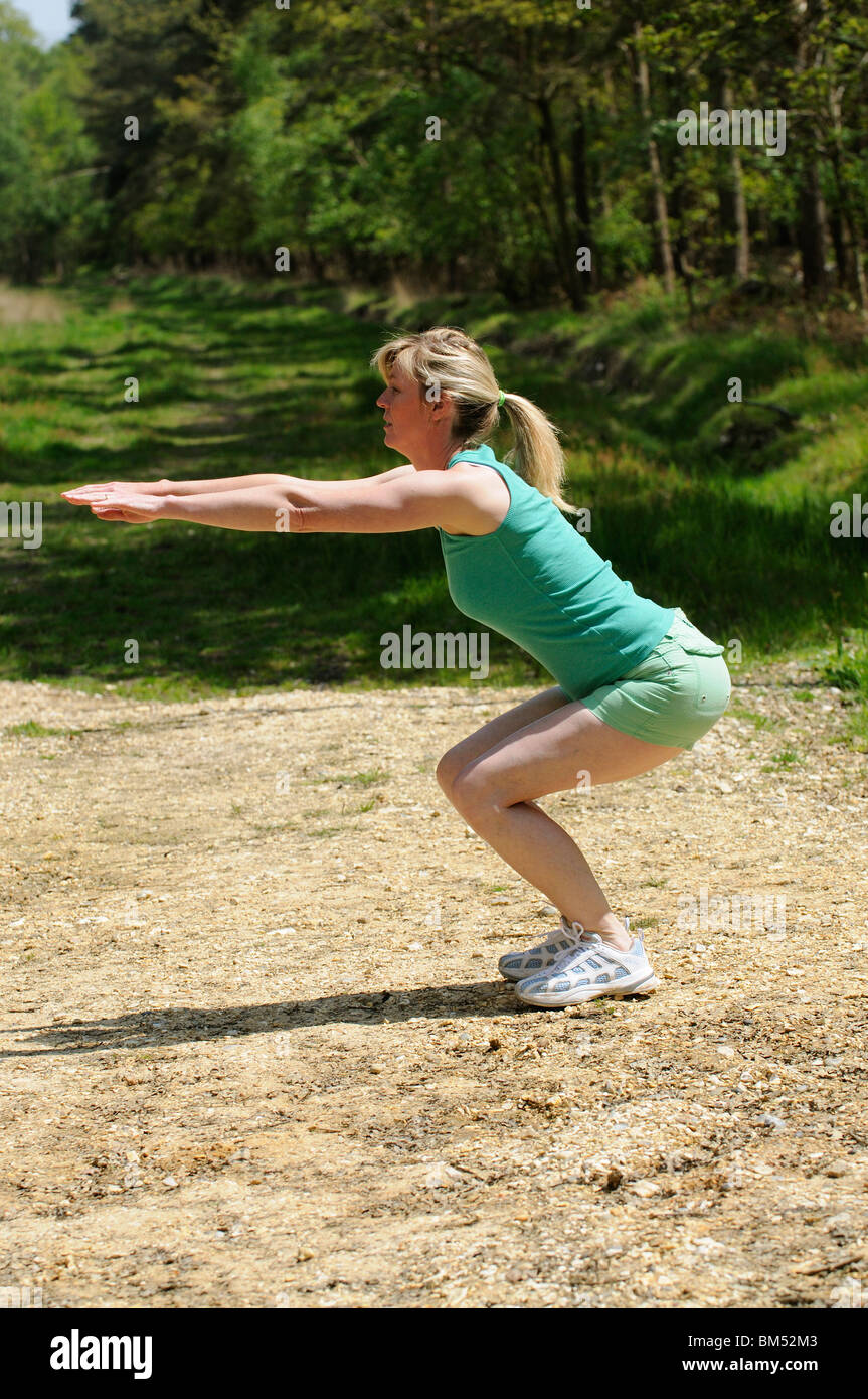 Woman in a squat position to keep & stay fit and healthy wearing green ...