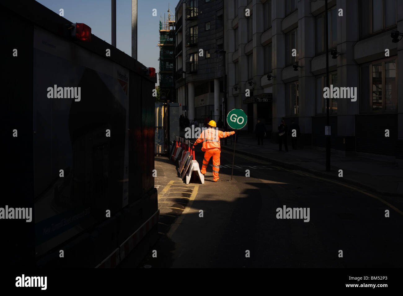 A Traffic Marshal dressed in a high-vis suit stands on a public road to ...