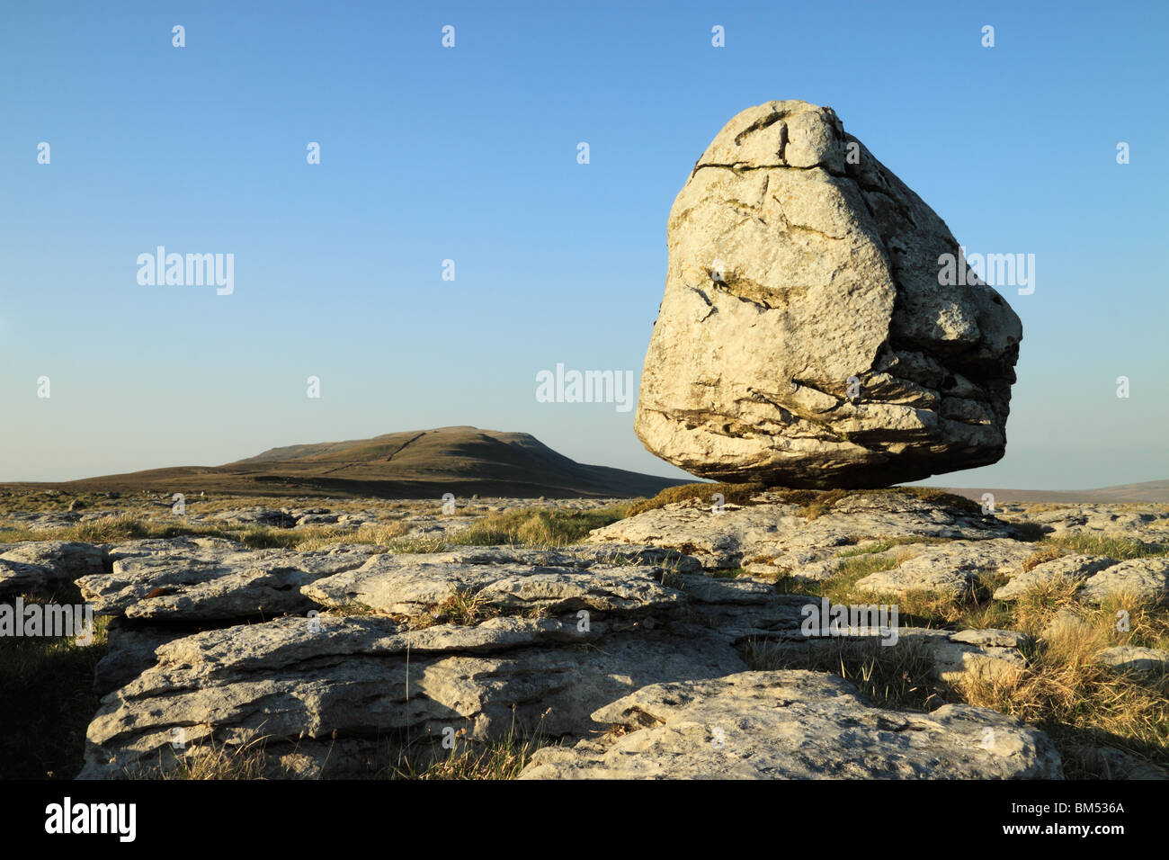 A boulder stands on limestone pavement with Whernside in the distance ...