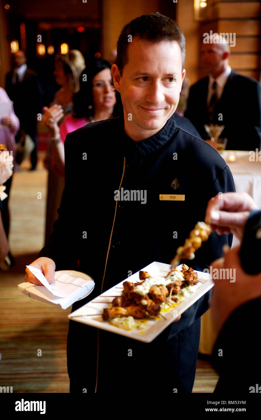 A waiter with a plate of chicken skewer hors d'oeuvres and appetizers ...