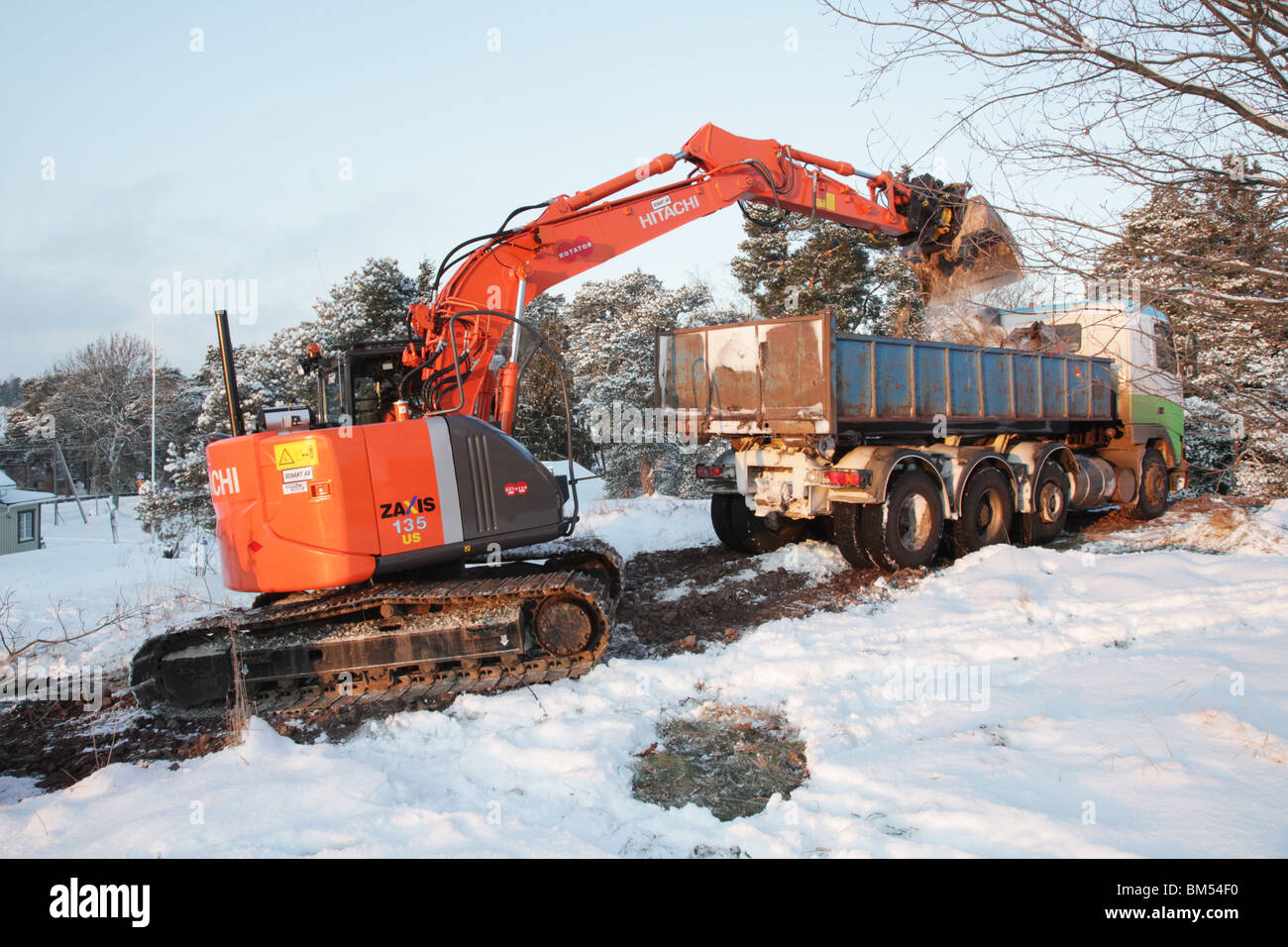 DIGGER FILLS LORRY IN FINLAND SNOW DEEP WINTER: A digger excavator ...