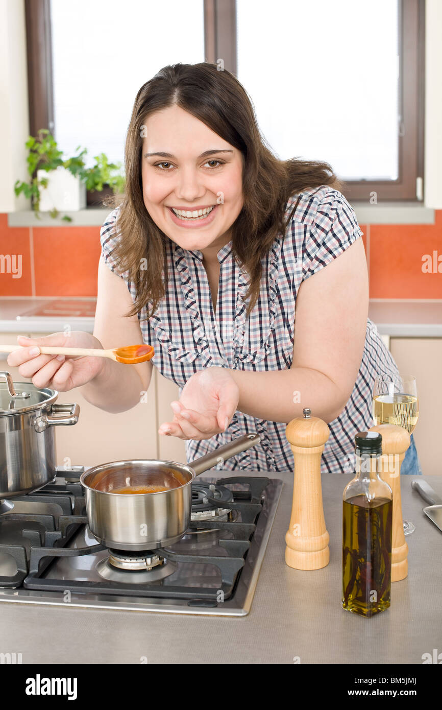 Cook - plus size woman tasting Italian tomato sauce in modern kitchen ...