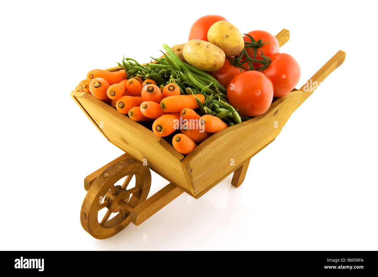 wooden wheelbarrow full with fresh vegetables isolated over white Stock ...