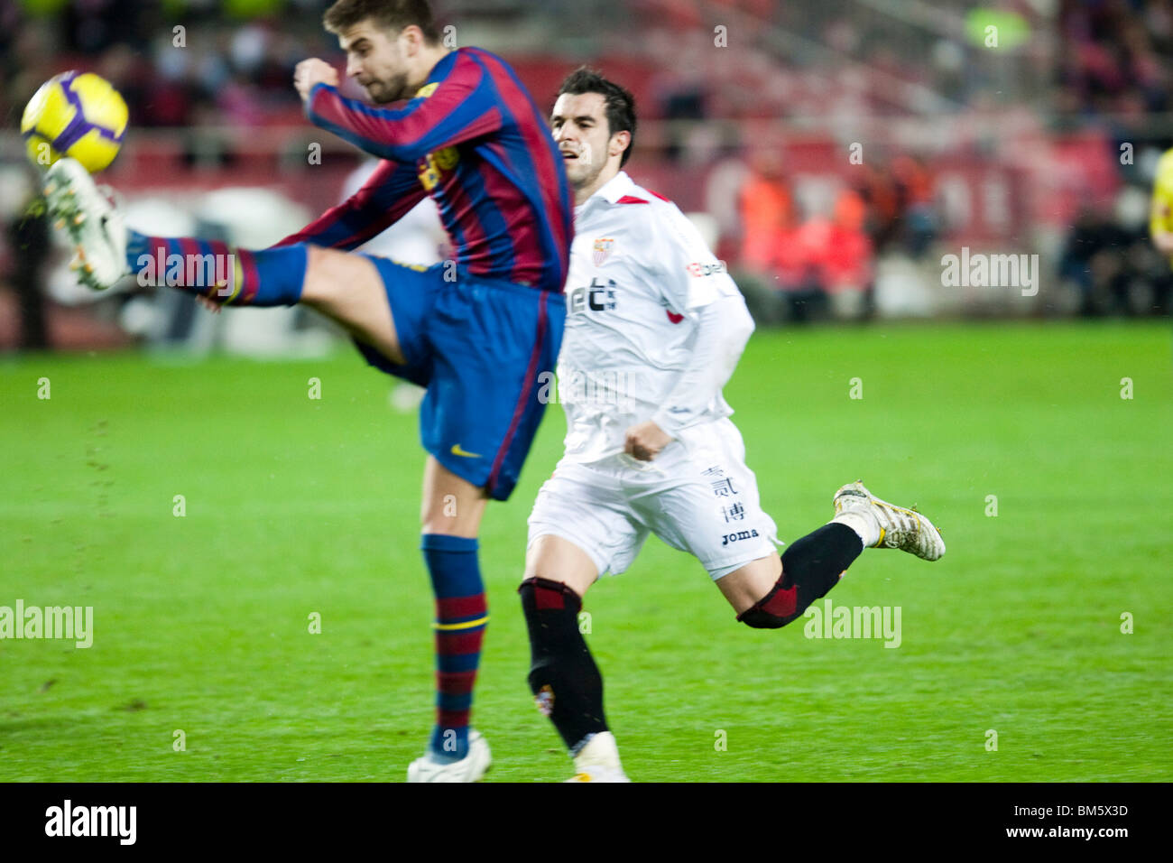 Pique kicking the ball before Negredo Stock Photo - Alamy