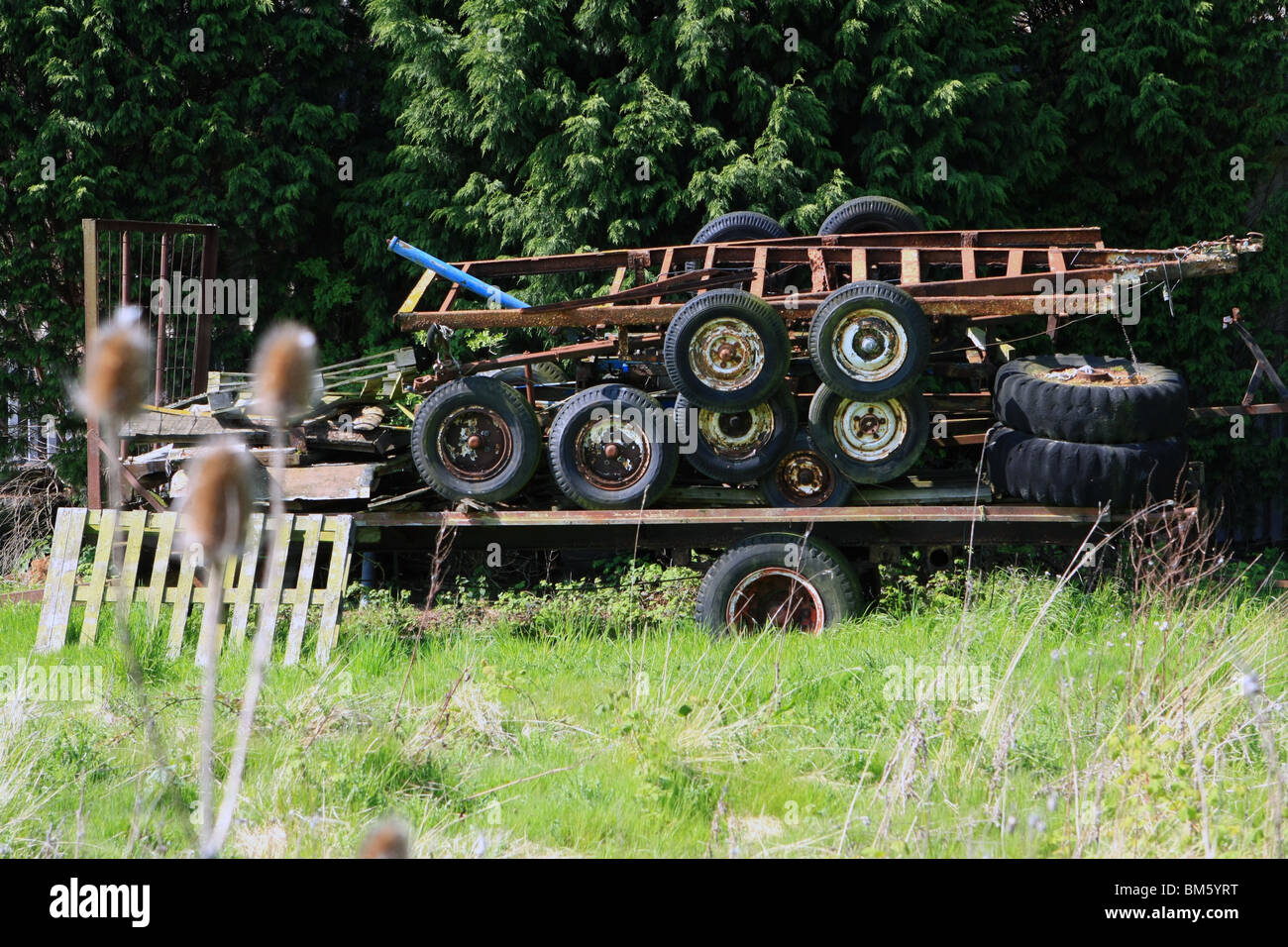 a broken trailer with rusty old trailers stacked on top, in front of ...