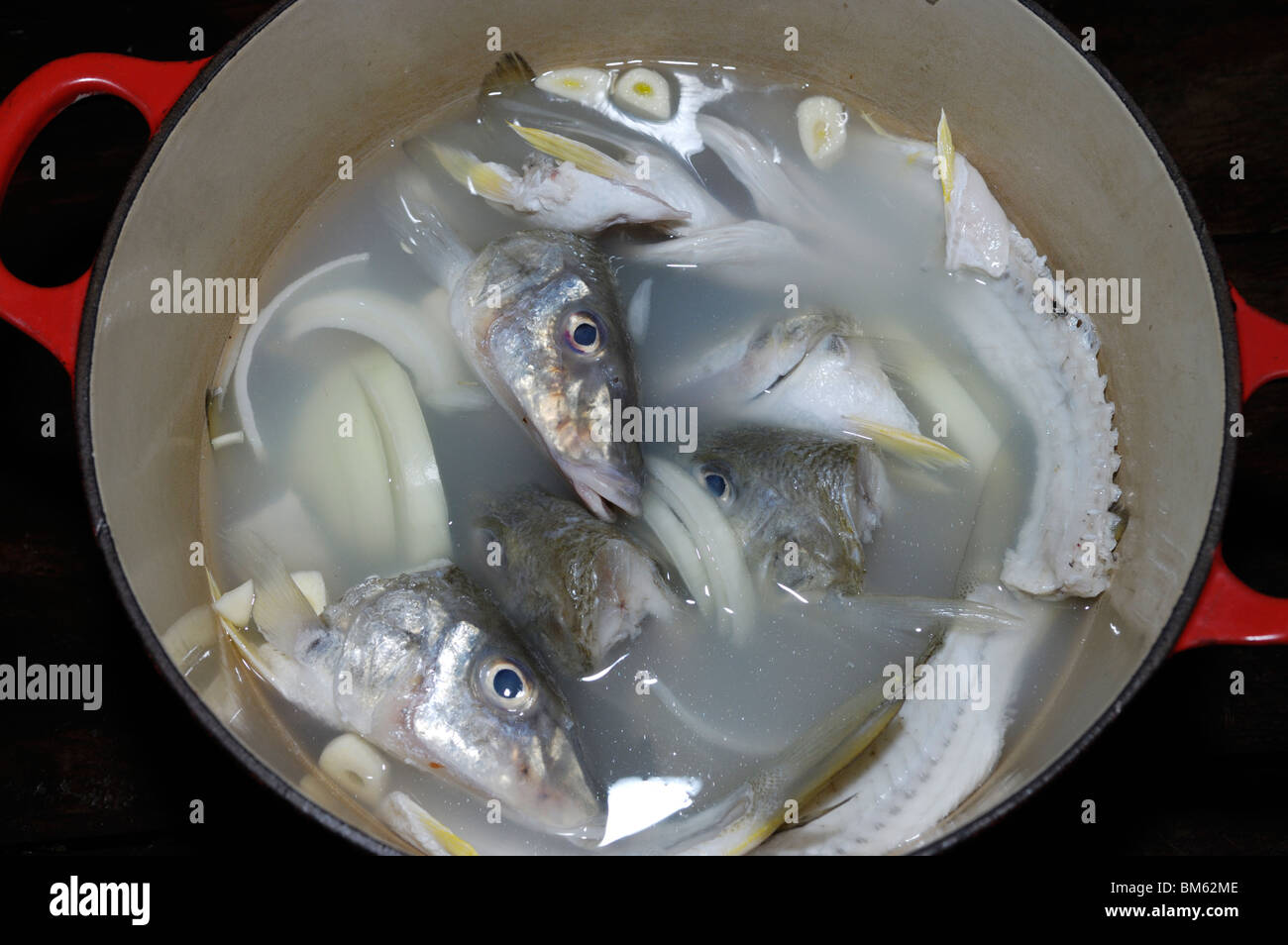 Fish stock being prepared in a cast iron pot using fish scraps (left ...