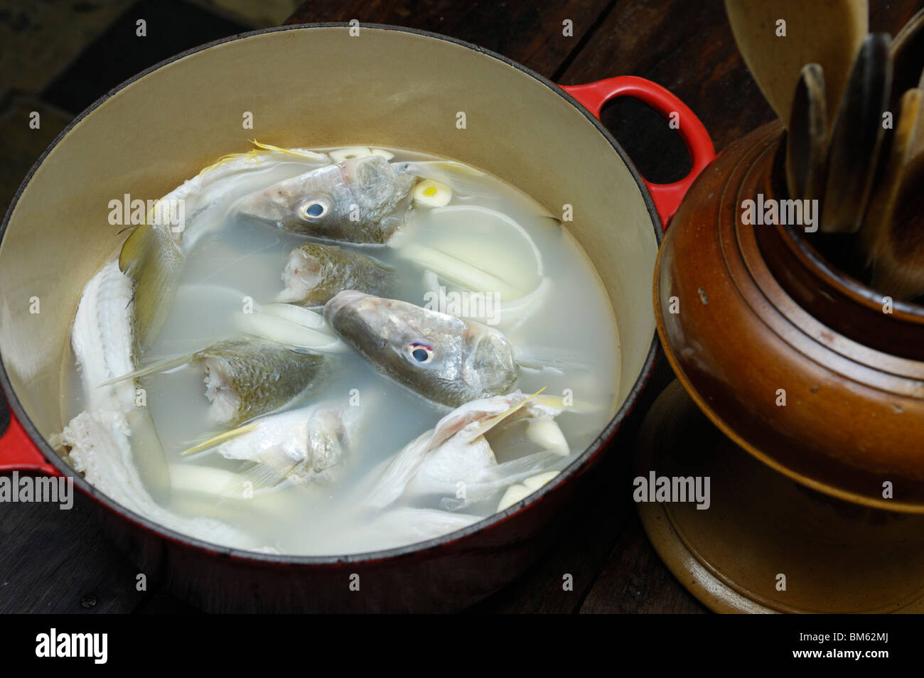 Fish stock being prepared in a cast iron pot using fish scraps (left ...