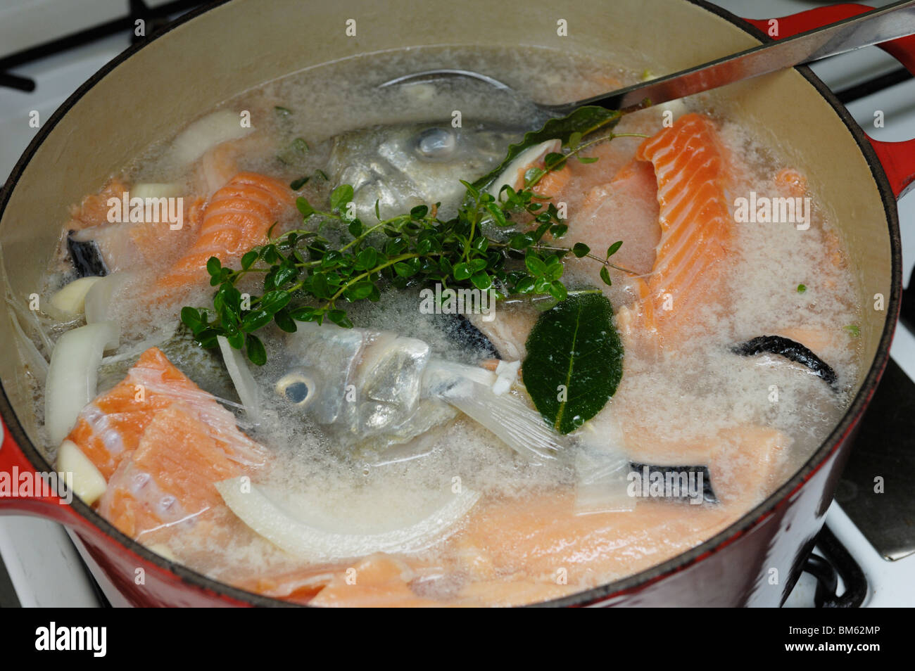 Fish stock being prepared in a cast iron pot using fish scraps (left ...