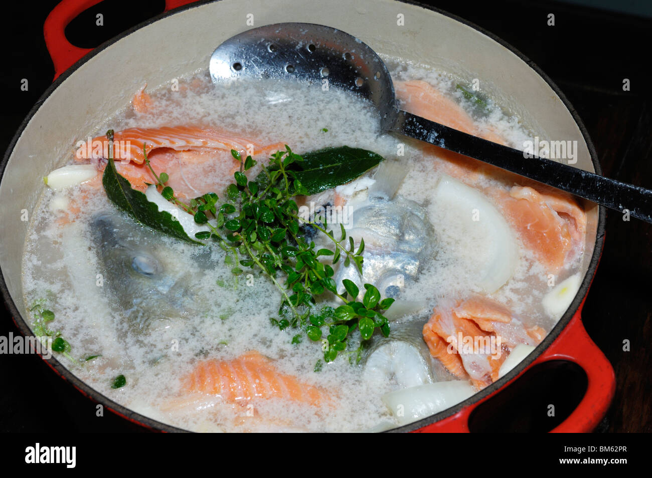 Fish stock being prepared in a cast iron pot using fish scraps (left ...