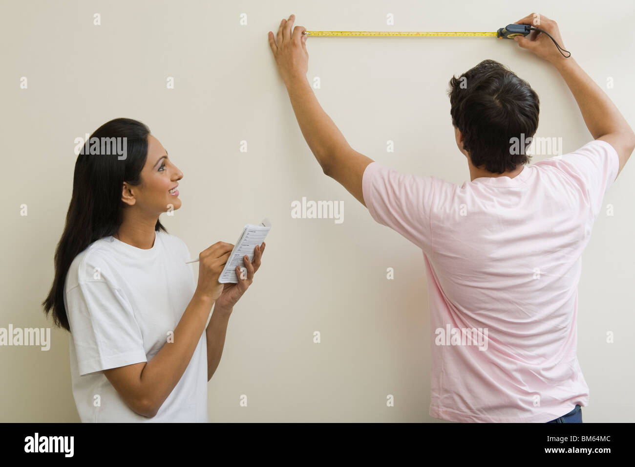 Couple measuring the wall with a tape measure Stock Photo - Alamy