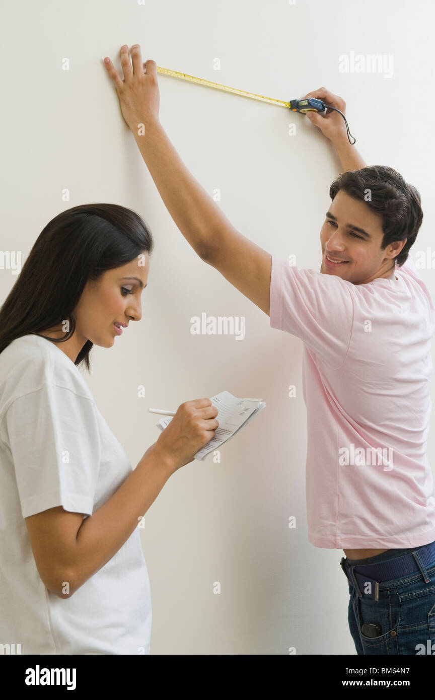 Couple measuring the wall with a tape measure Stock Photo - Alamy