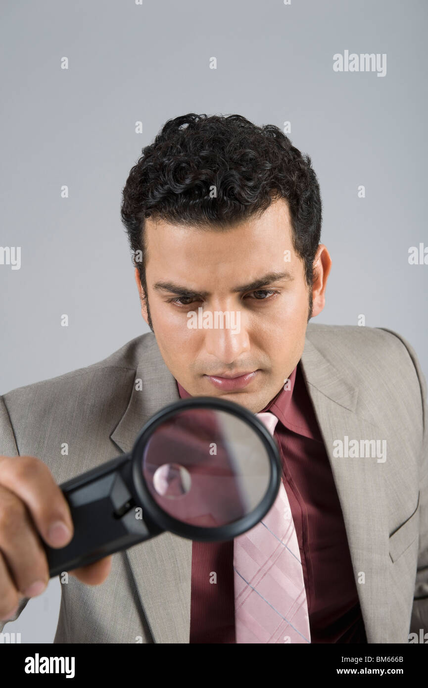 Businessman looking through a magnifying glass Stock Photo - Alamy