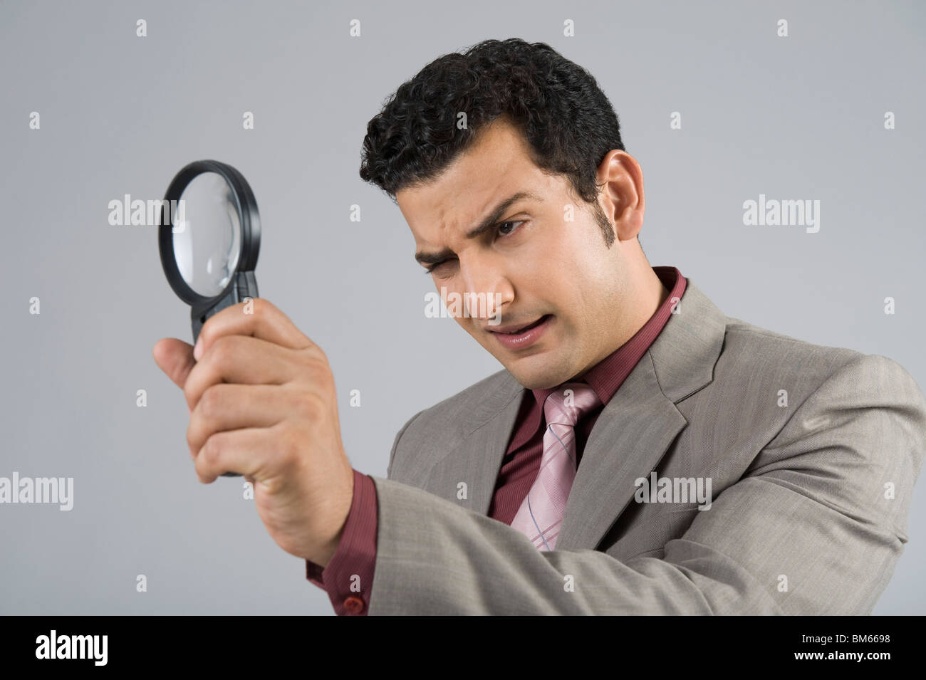 Businessman looking through a magnifying glass Stock Photo - Alamy