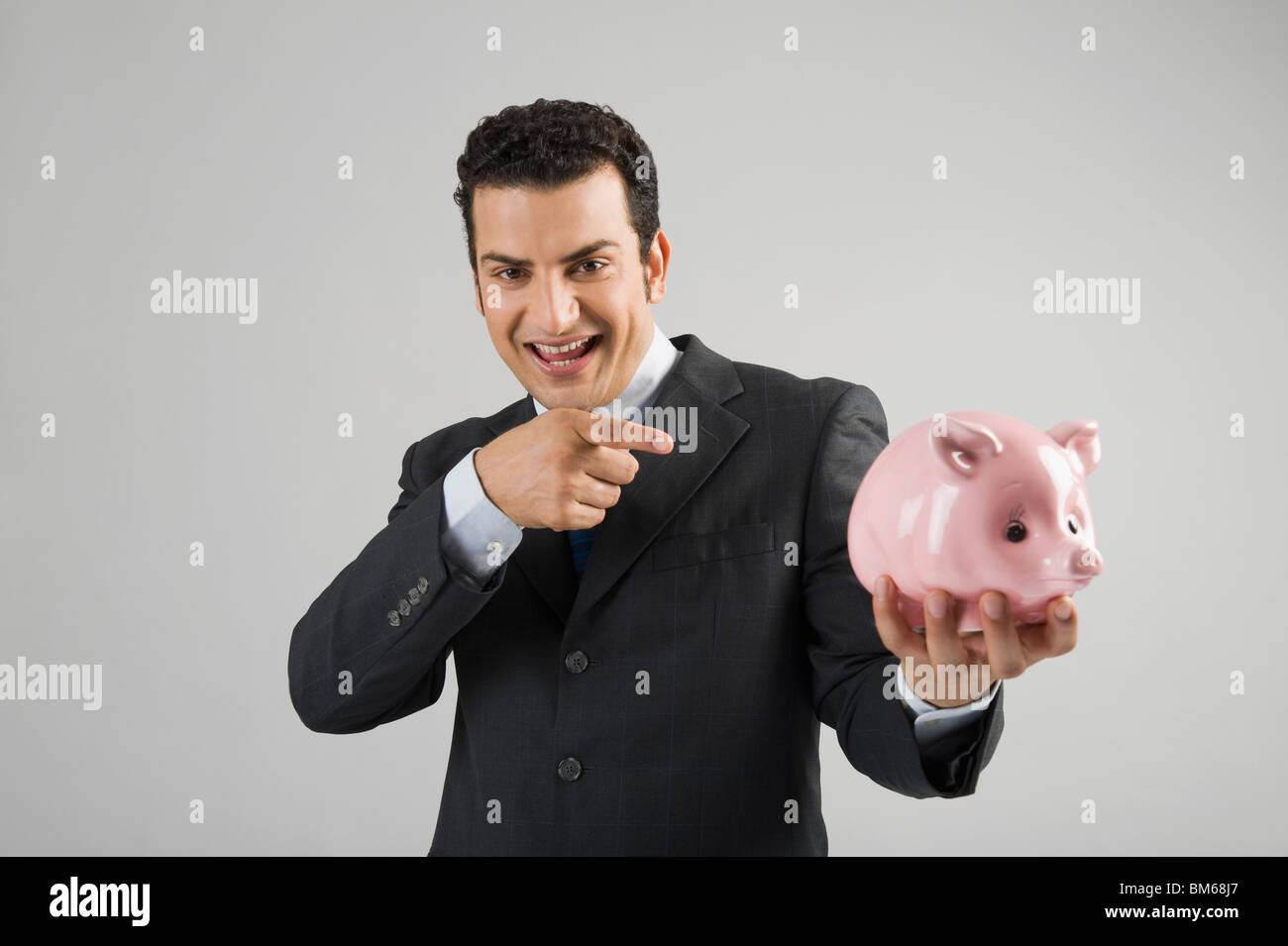 Portrait of a businessman pointing at a piggy bank Stock Photo - Alamy