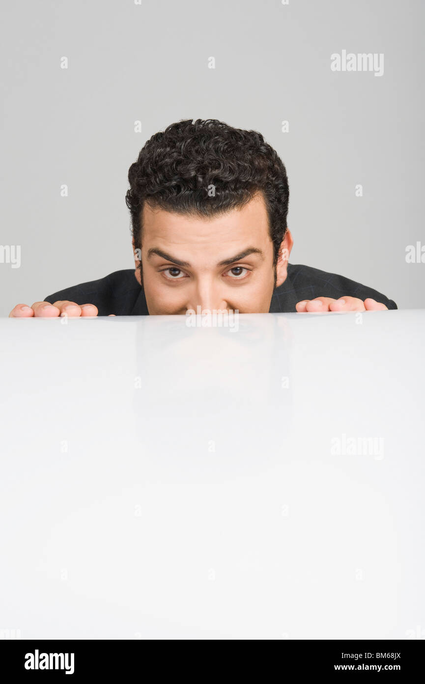 Businessman peeking over a desk Stock Photo - Alamy