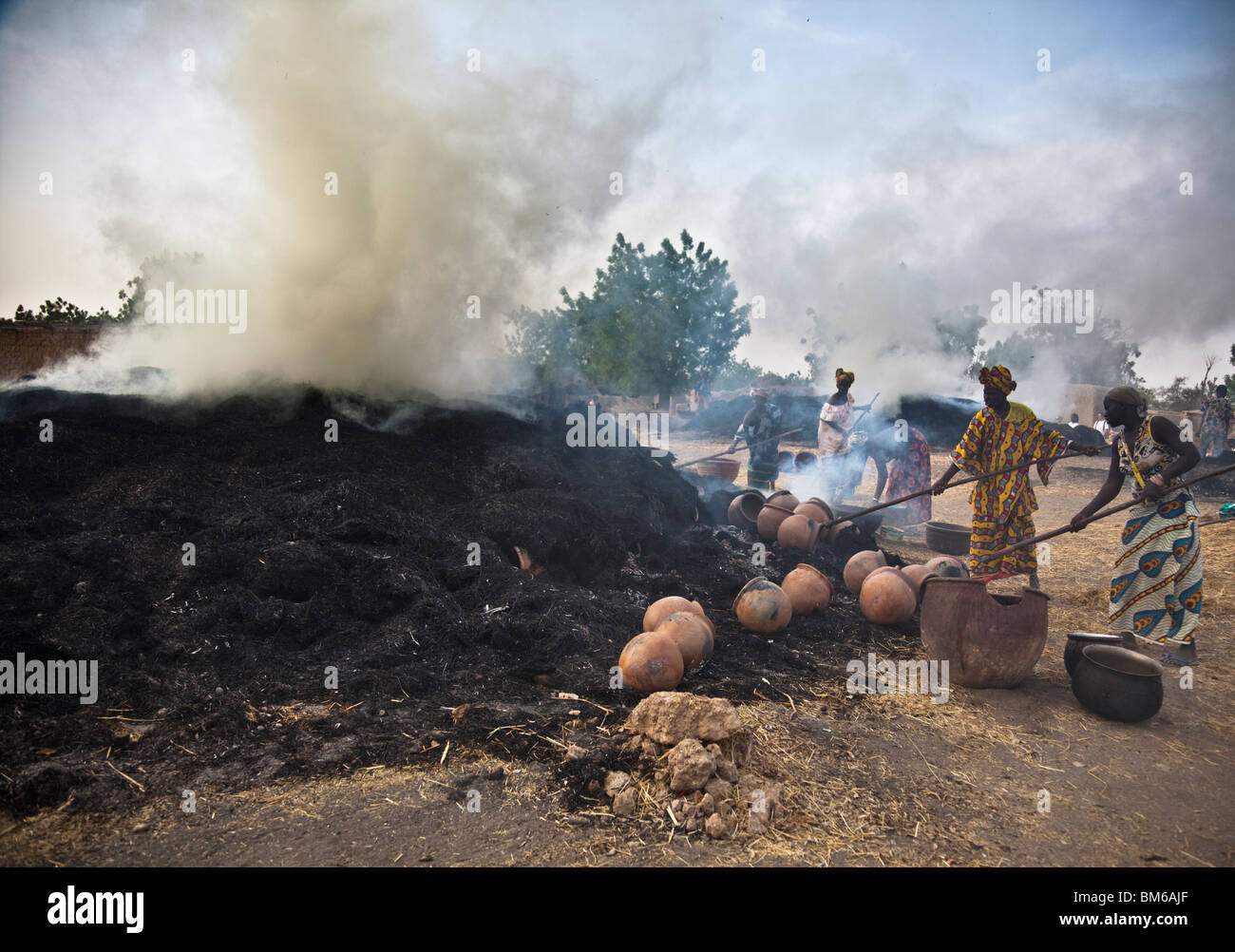 Women in Mali remove pottery from the kilns using hooked poles. The ...