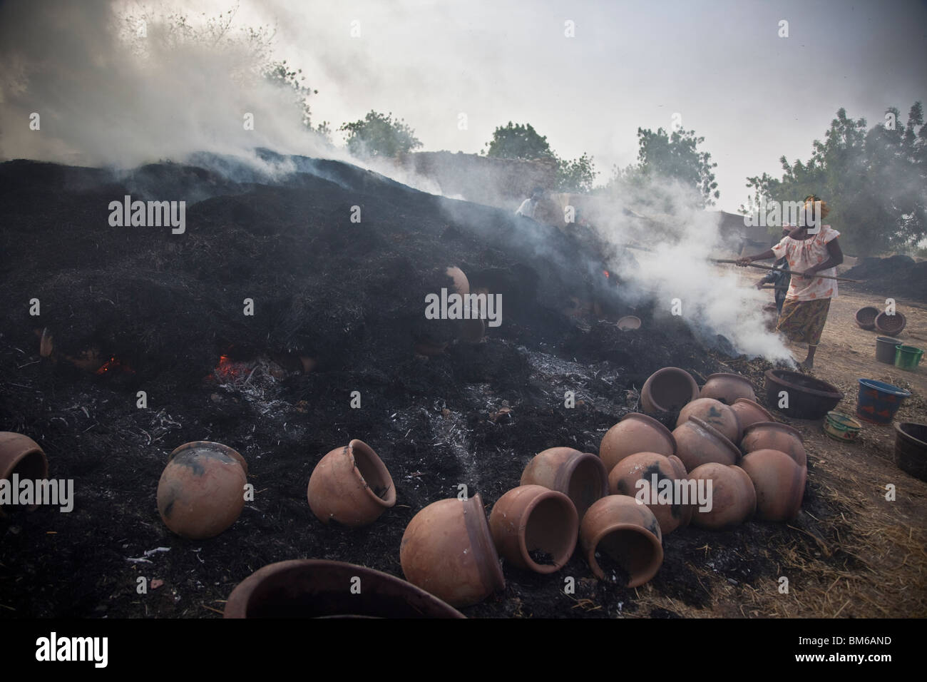 Women in Mali remove pottery from the kilns using hooked poles. The ...