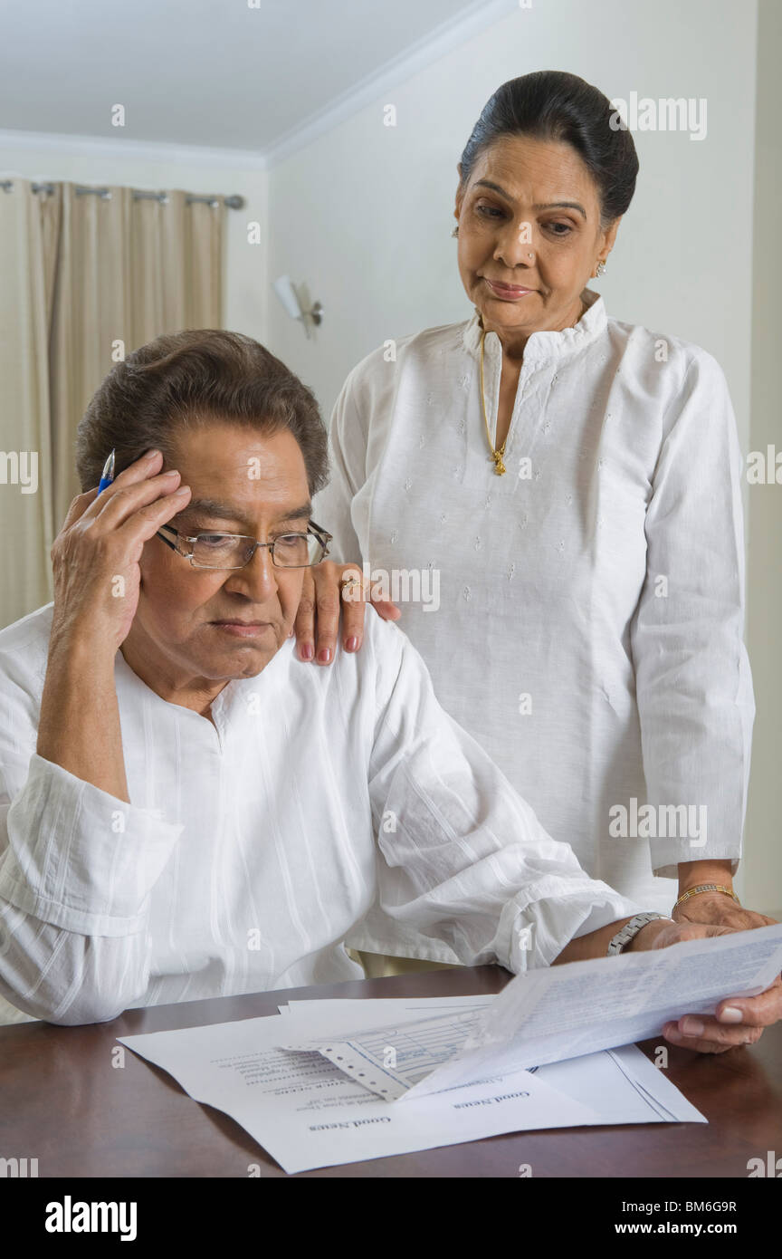 Man looking at a bill with a woman standing beside him Stock Photo - Alamy