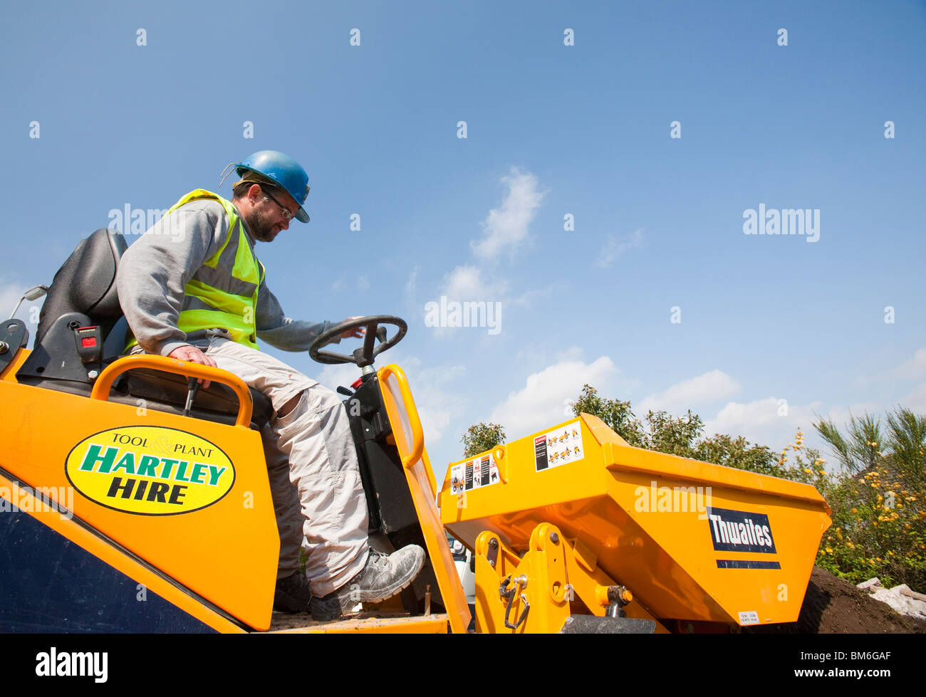A builder driving a mini dumper truck on a house extension, building ...