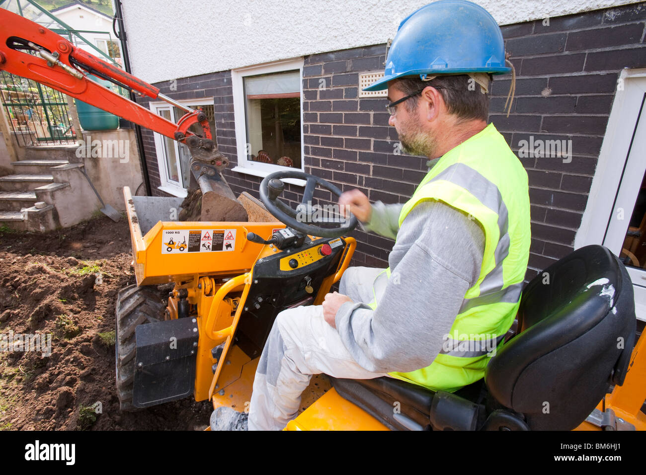 A mine digger and mini dumper truck on a house extension, building job ...