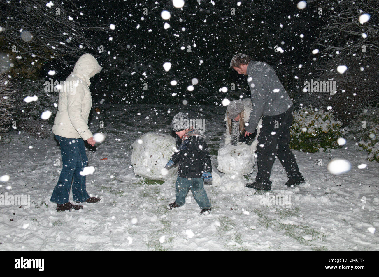 family mother father son grandmother in heavy snow at night building ...