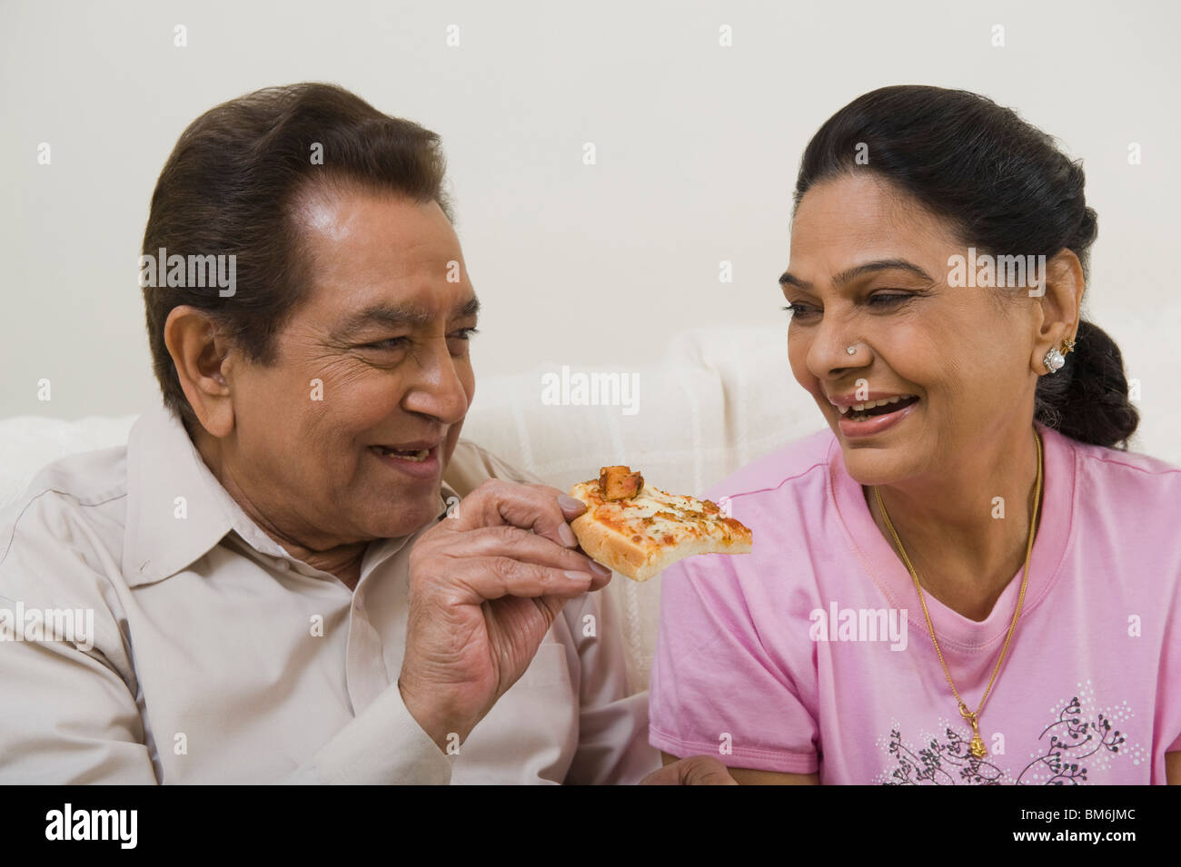 Man feeding a slice of pizza her wife Stock Photo - Alamy