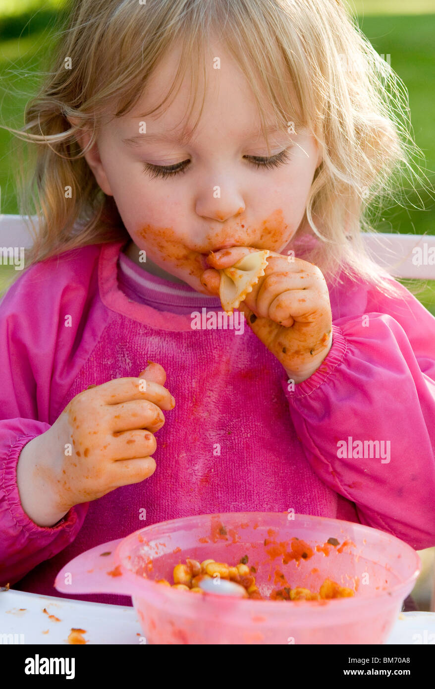 GIRL TODDLER, ENJOYS GETTING MESSY WHILE EATING PASTA IN TOMATO SAUCE ...
