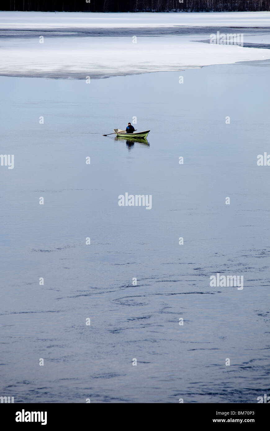 Fisherman fishing from a rowboat / skiff at early spring , Finland ...