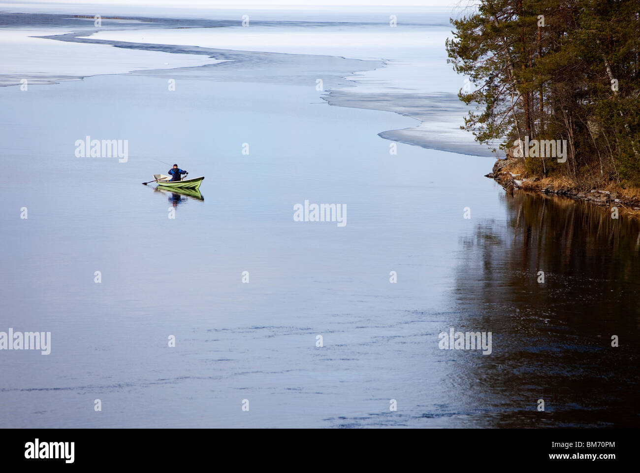 Fisherman fishing from a rowboat / skiff at early spring , Finland ...