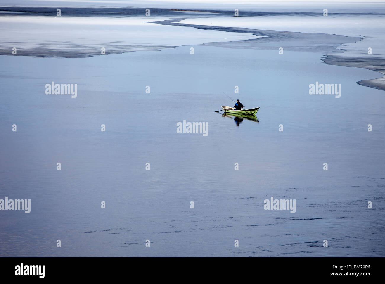 Fisherman fishing from a rowboat / skiff at early spring , Finland ...