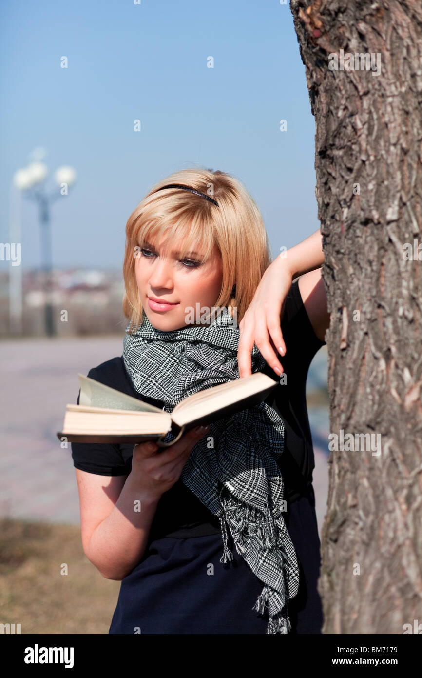 Thoughtful young woman reading a book Stock Photo - Alamy